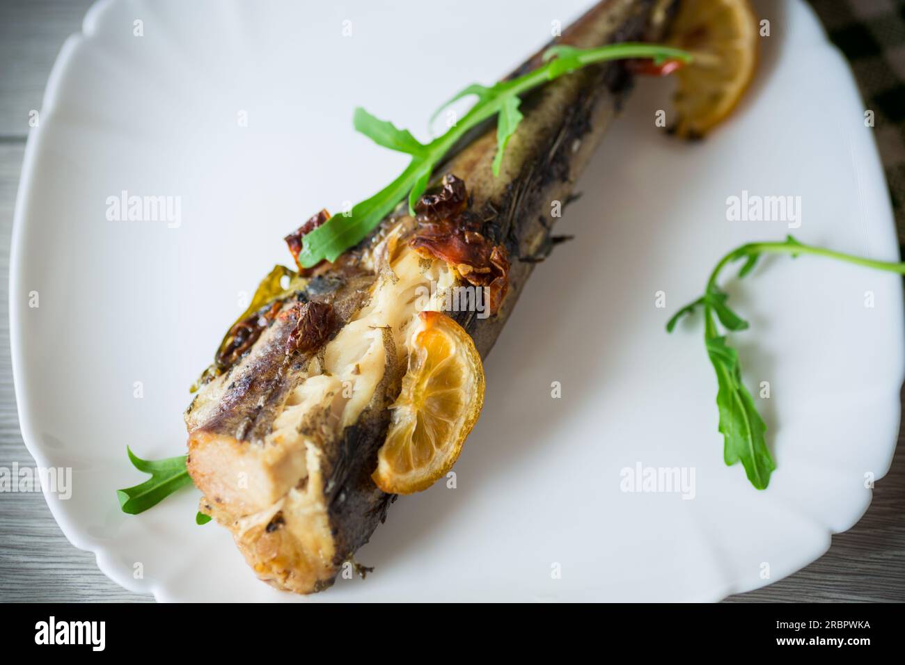 Baked fish with seasonings and spices in a plate on a wooden table ...