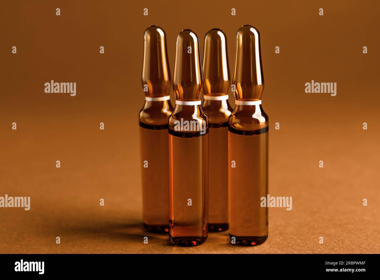 Glass ampules on brown background Stock Photo - Alamy