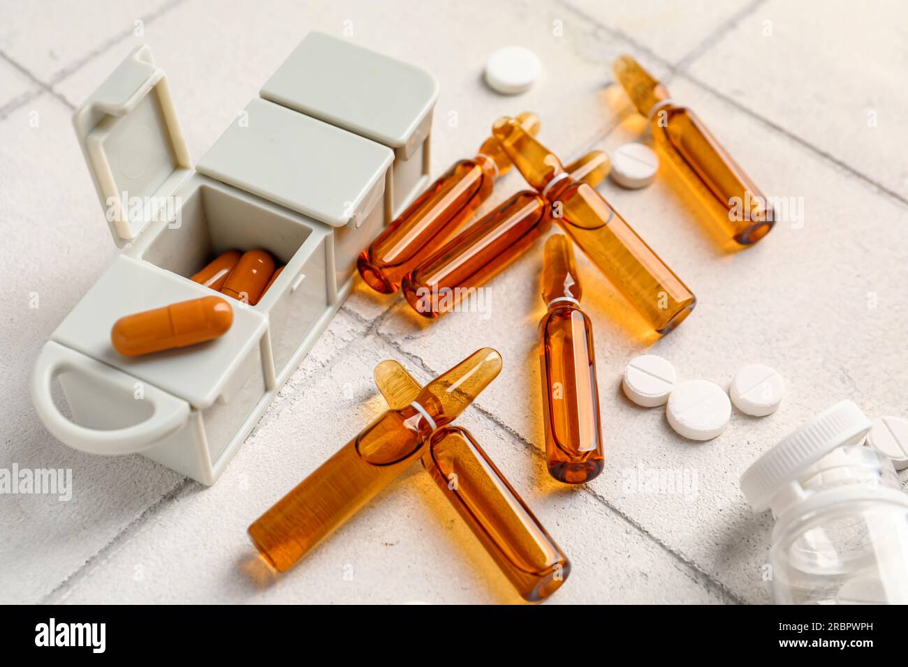 Medical ampules and pills on white tile background Stock Photo - Alamy