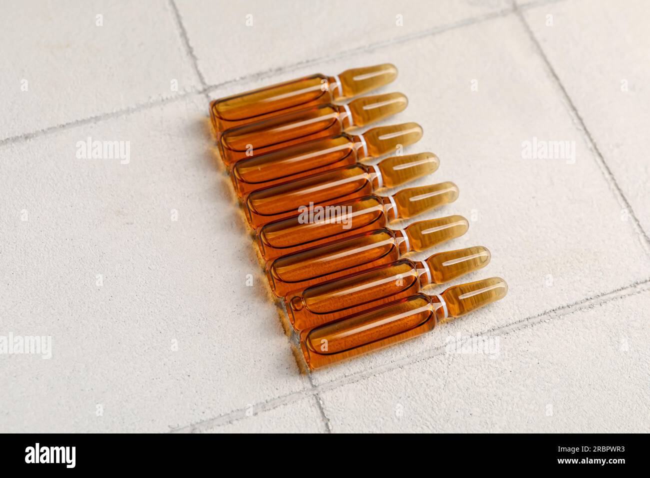 Medical ampules on white tile background Stock Photo - Alamy