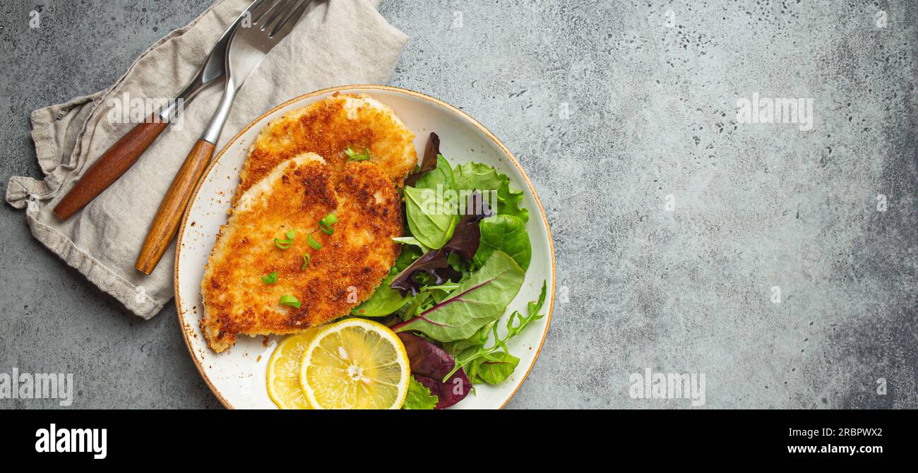 Crispy panko breaded fried chicken fillet with green salad and lemon on ...