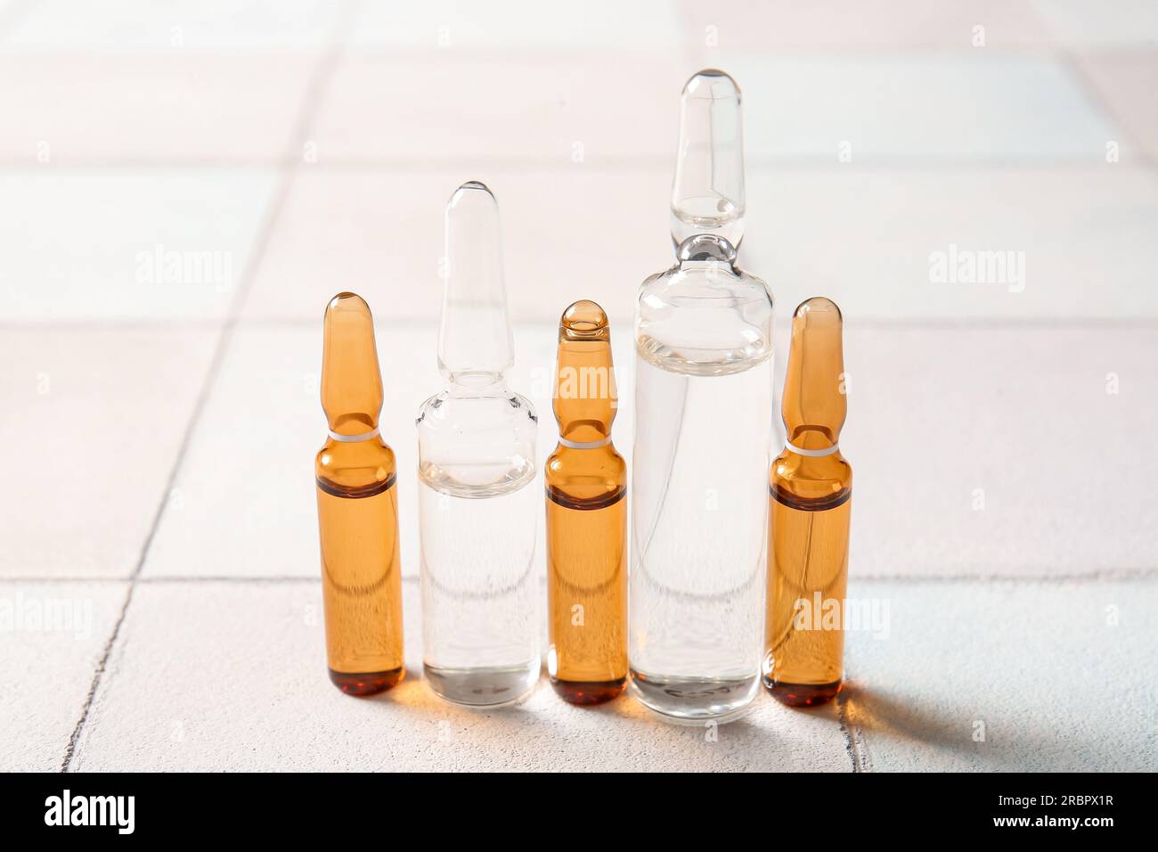 Glass medical ampules on white tile background Stock Photo - Alamy