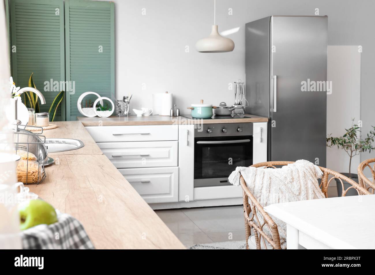 Interior of light kitchen with stylish fridge, counters, table and ...