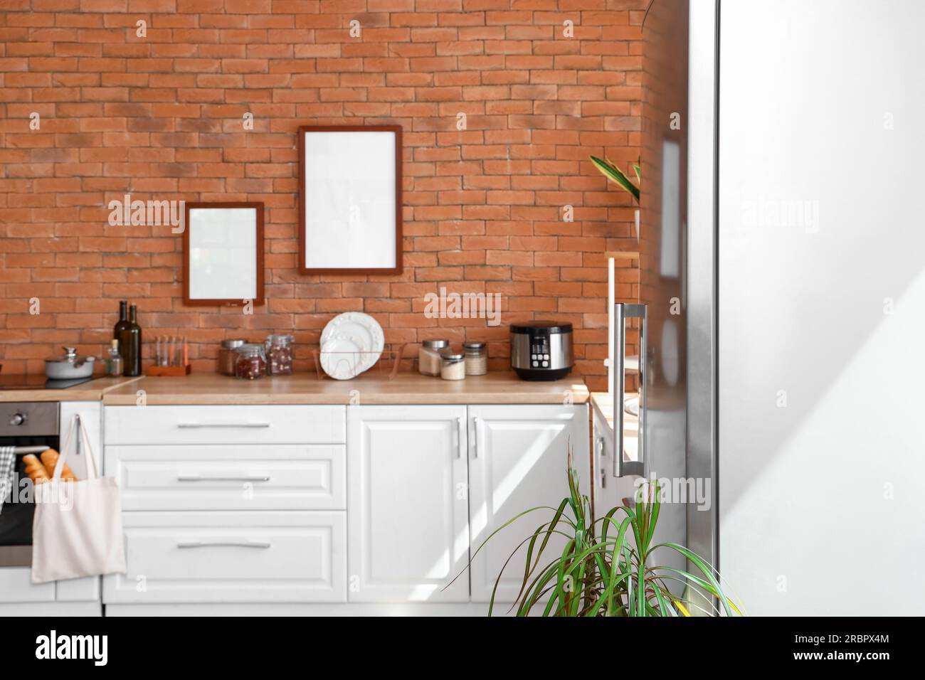 Interior of kitchen with stylish fridge, counters and blank pictures ...