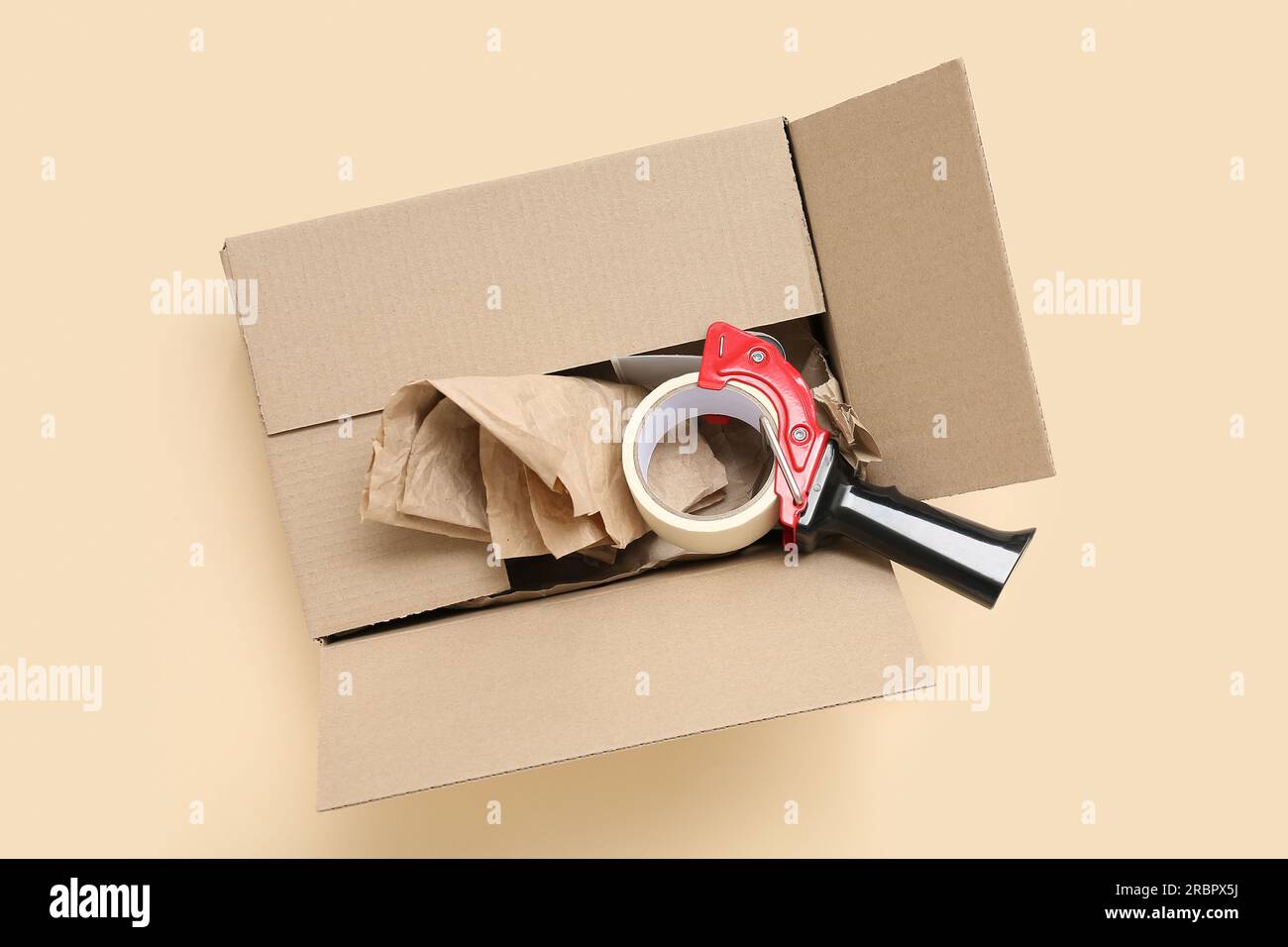 Packing tape dispenser and cardboard box on beige background Stock ...
