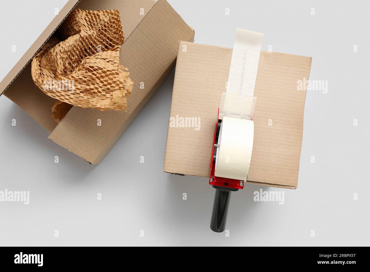 Packing tape dispenser, cardboard boxes and crumpled paper on grey ...