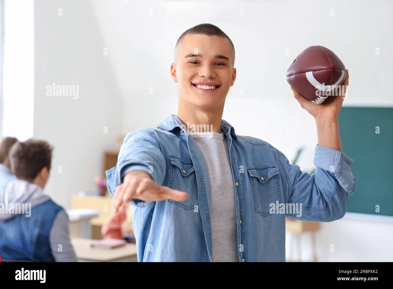 Male student with rugby ball in classroom Stock Photo - Alamy