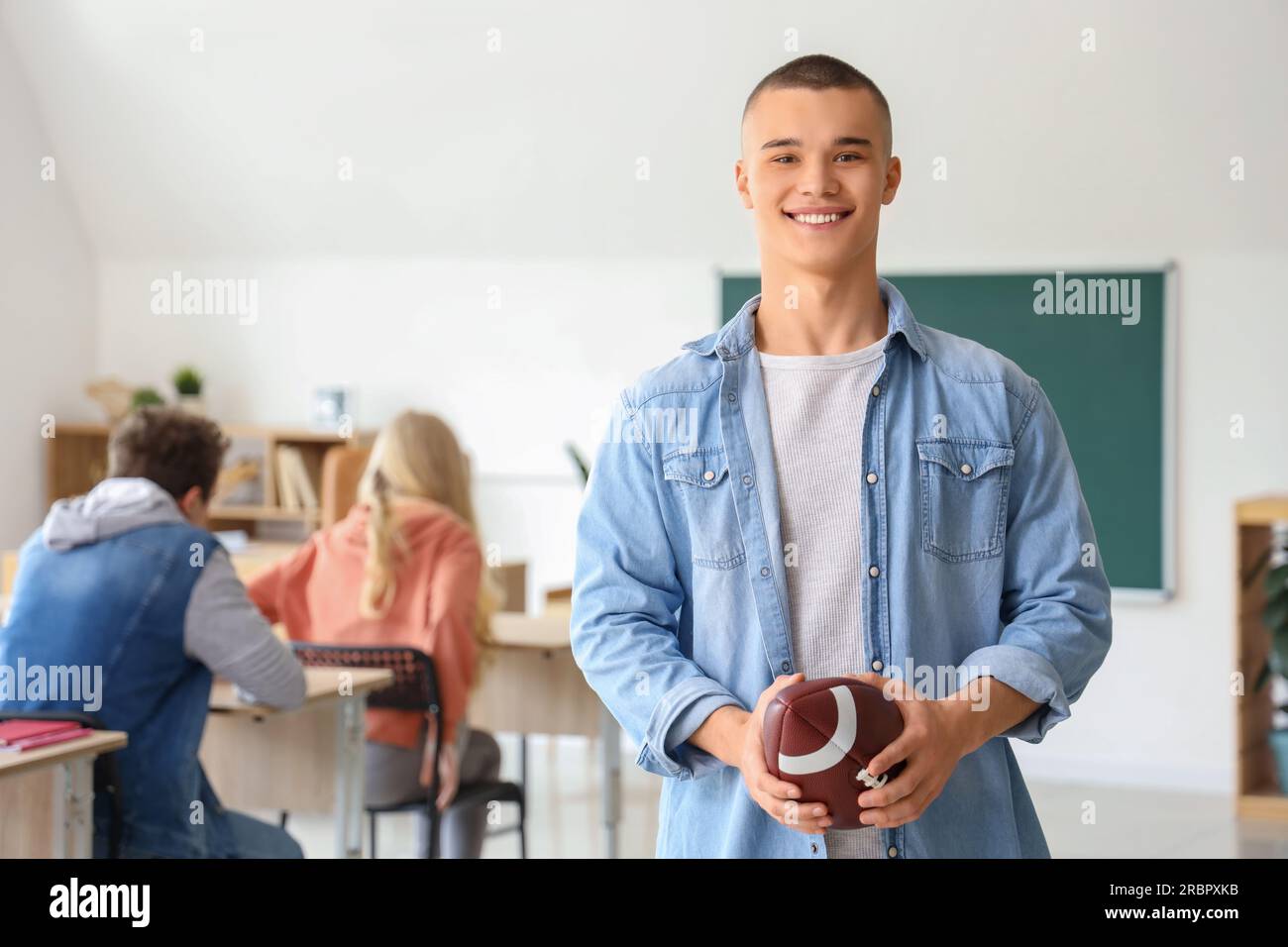 Male student with rugby ball in classroom Stock Photo - Alamy