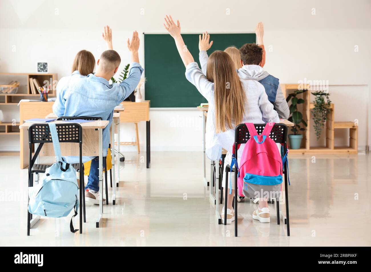 Classmates raising hands to answer in classroom Stock Photo - Alamy