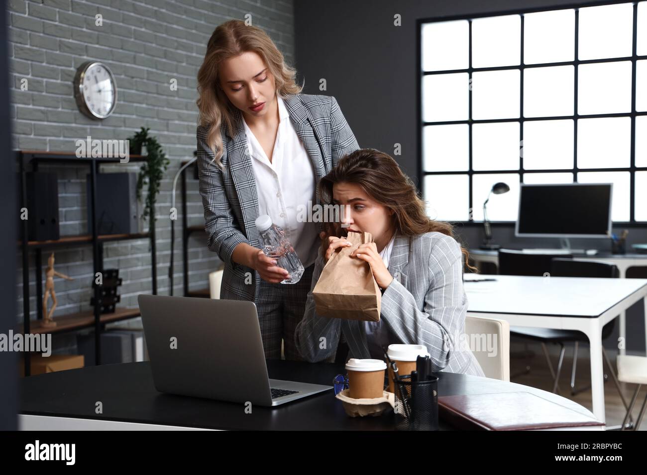 Woman helping her colleague who is having panic attack in office Stock ...