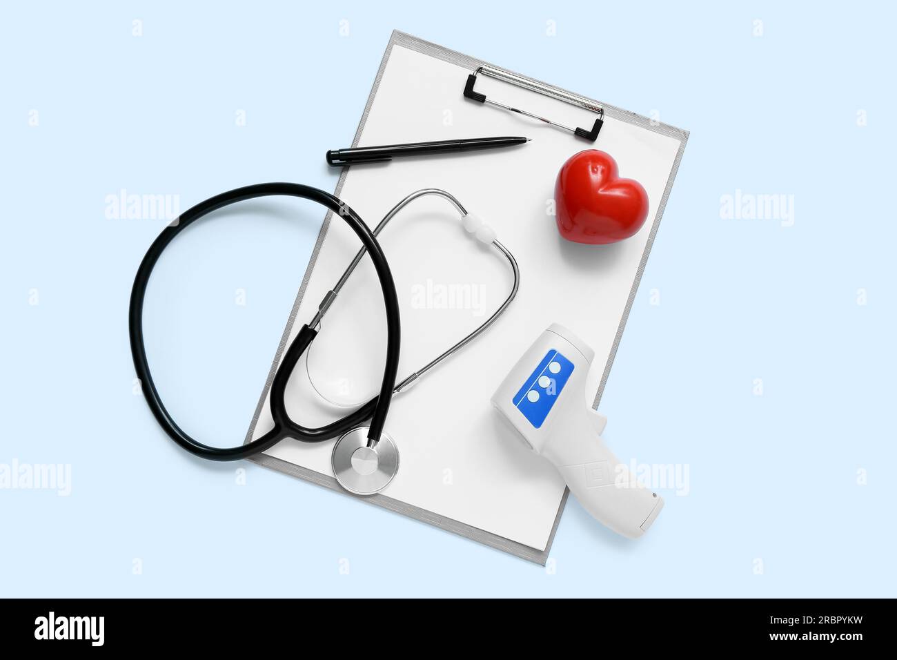 Stethoscope, infrared thermometer, heart and clipboard on grey ...