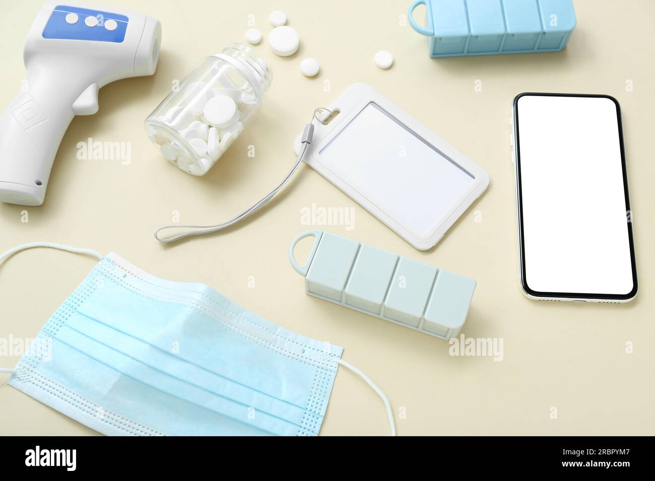 Mobile phone, badge, pillbox, infrared thermometer, pills and mask on ...