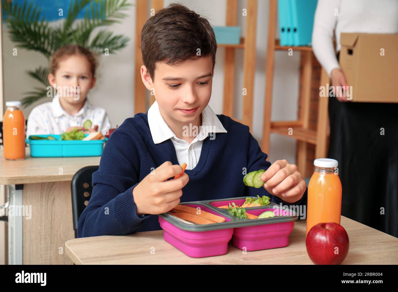 Little boy eating lunch in classroom Stock Photo - Alamy