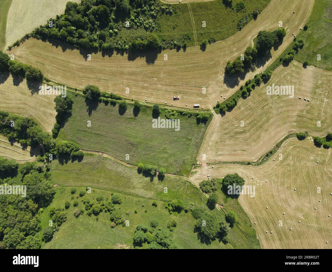 View from very height of green grass fields with hay bales and trees in ...