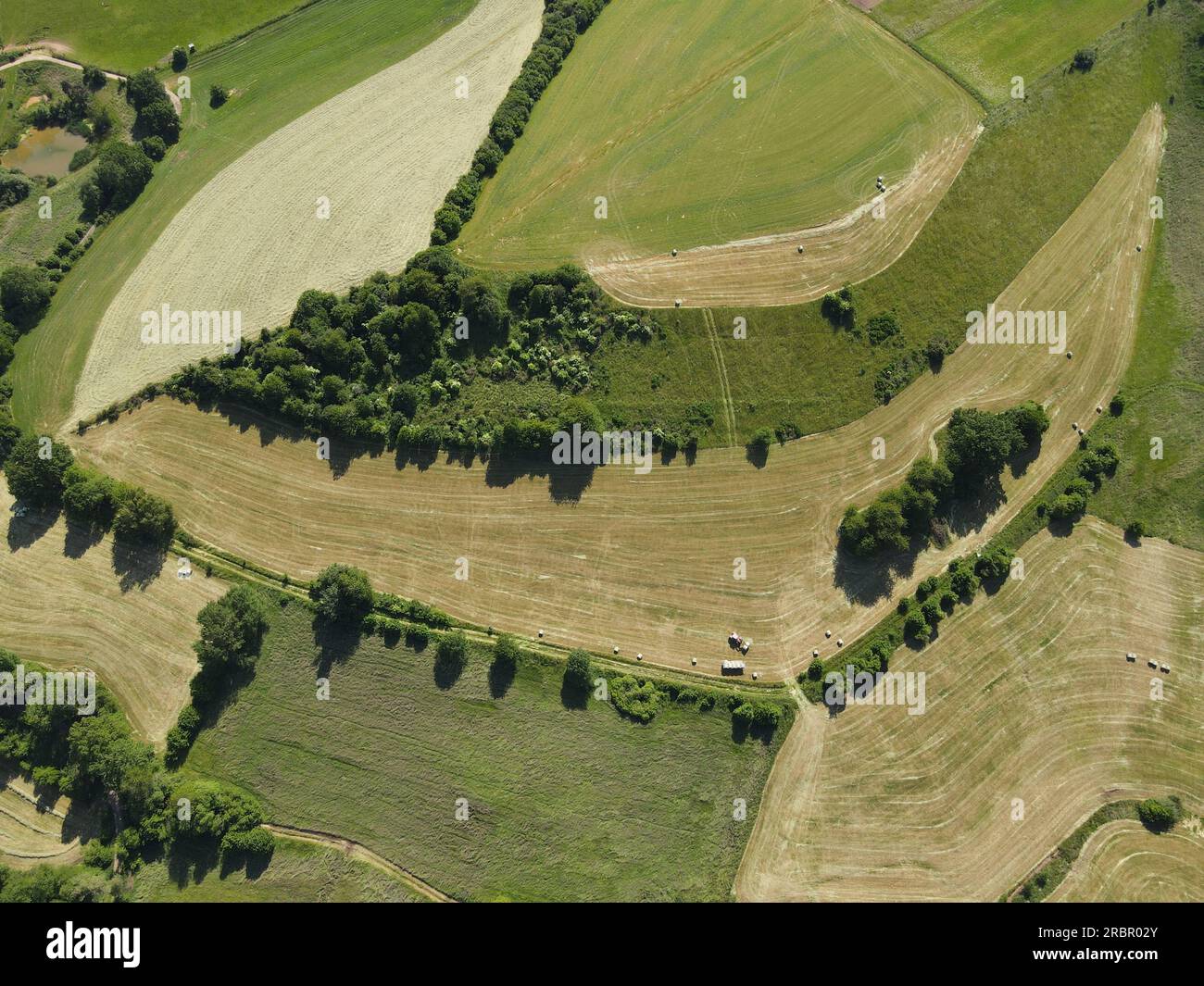 View from very height of green grass fields with hay bales and trees in ...