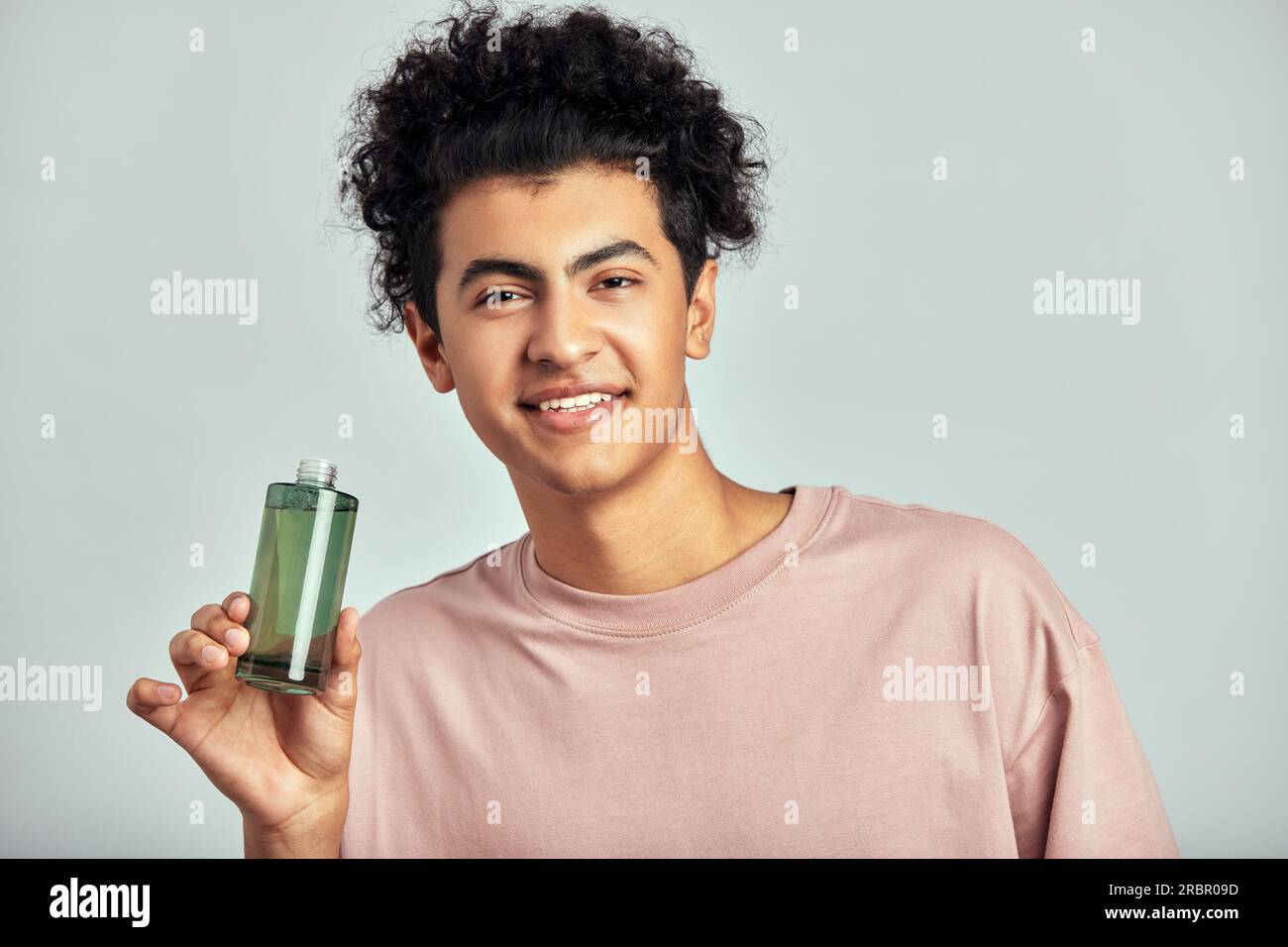Portrait of young handsome smiling guy with a bottle of facial lotion ...