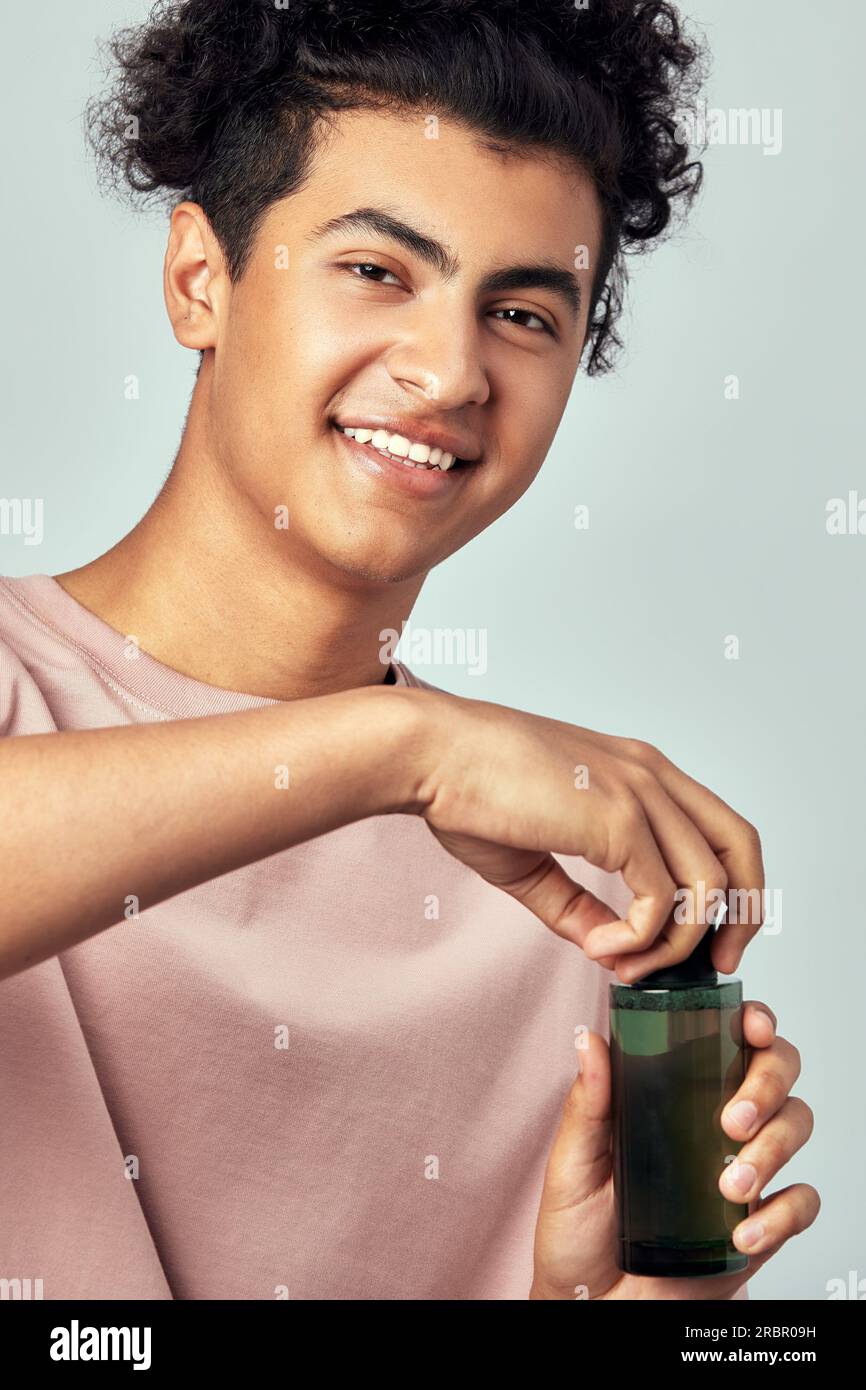 Portrait of young handsome smiling guy with a bottle of facial lotion ...