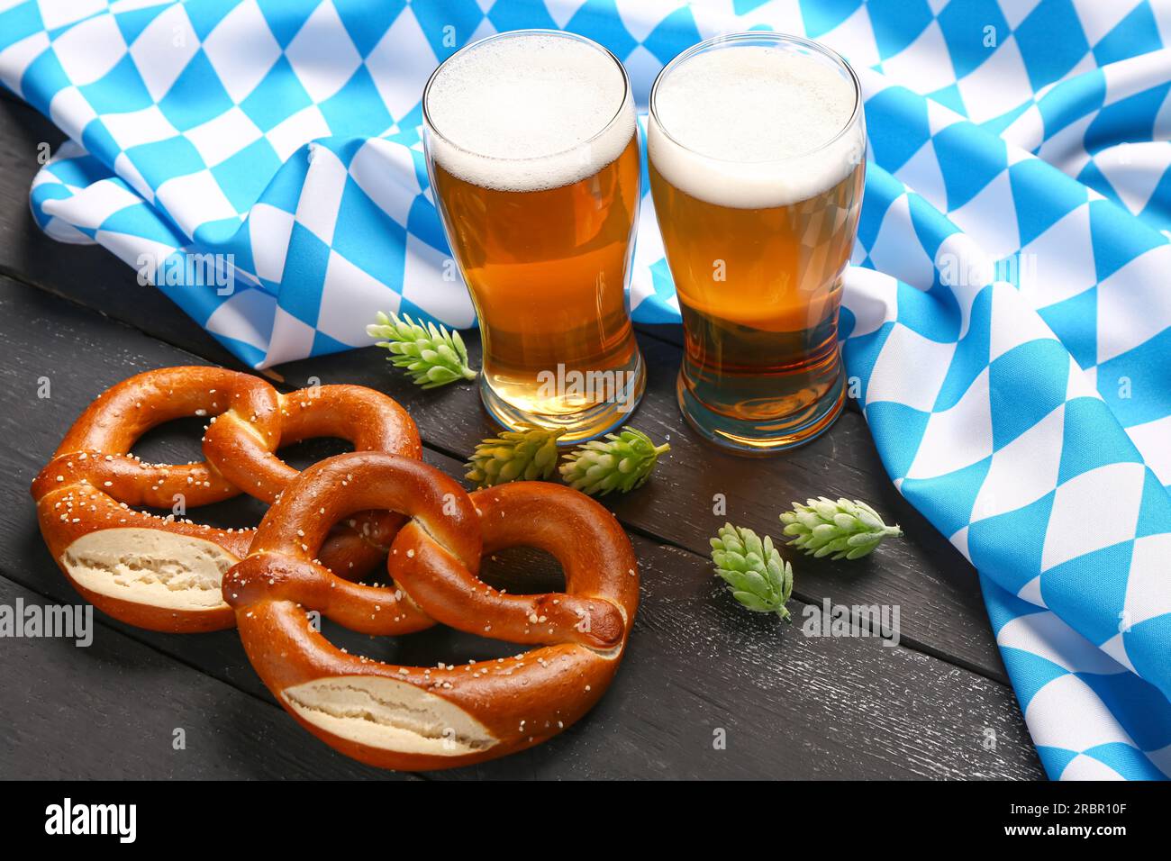 Flag of Bavaria, mugs with beer and pretzels on black wooden background ...