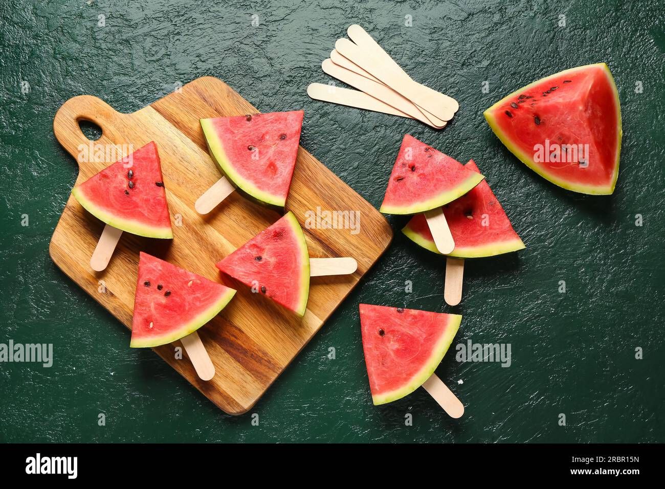 Wooden board with sweet watermelon sticks on green background Stock ...