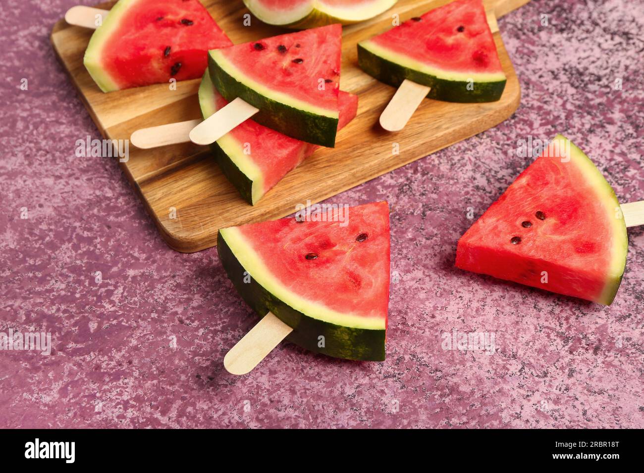 Wooden board with sweet watermelon sticks on purple background Stock ...