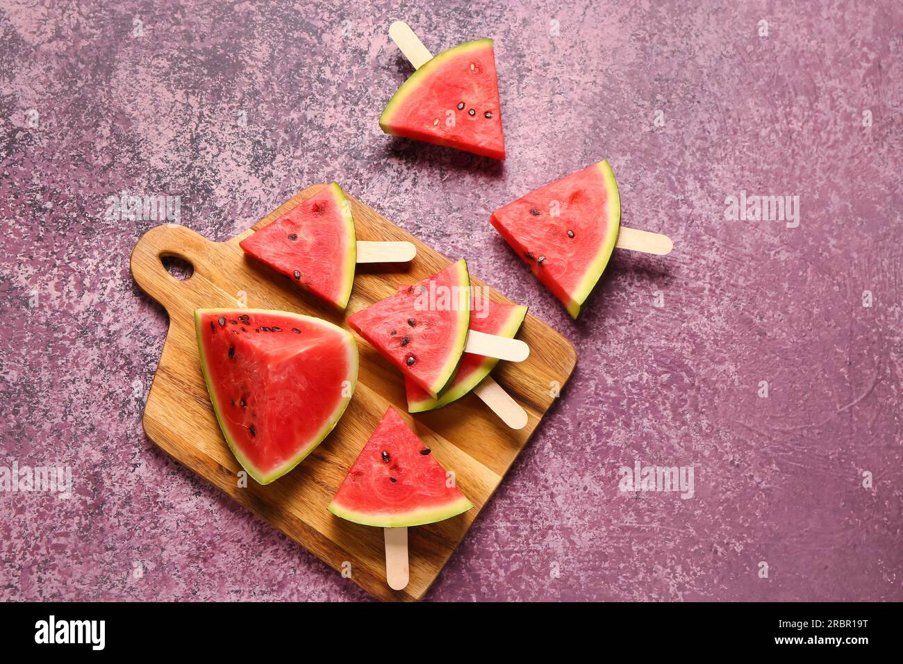 Wooden board with sweet watermelon sticks on purple background Stock ...