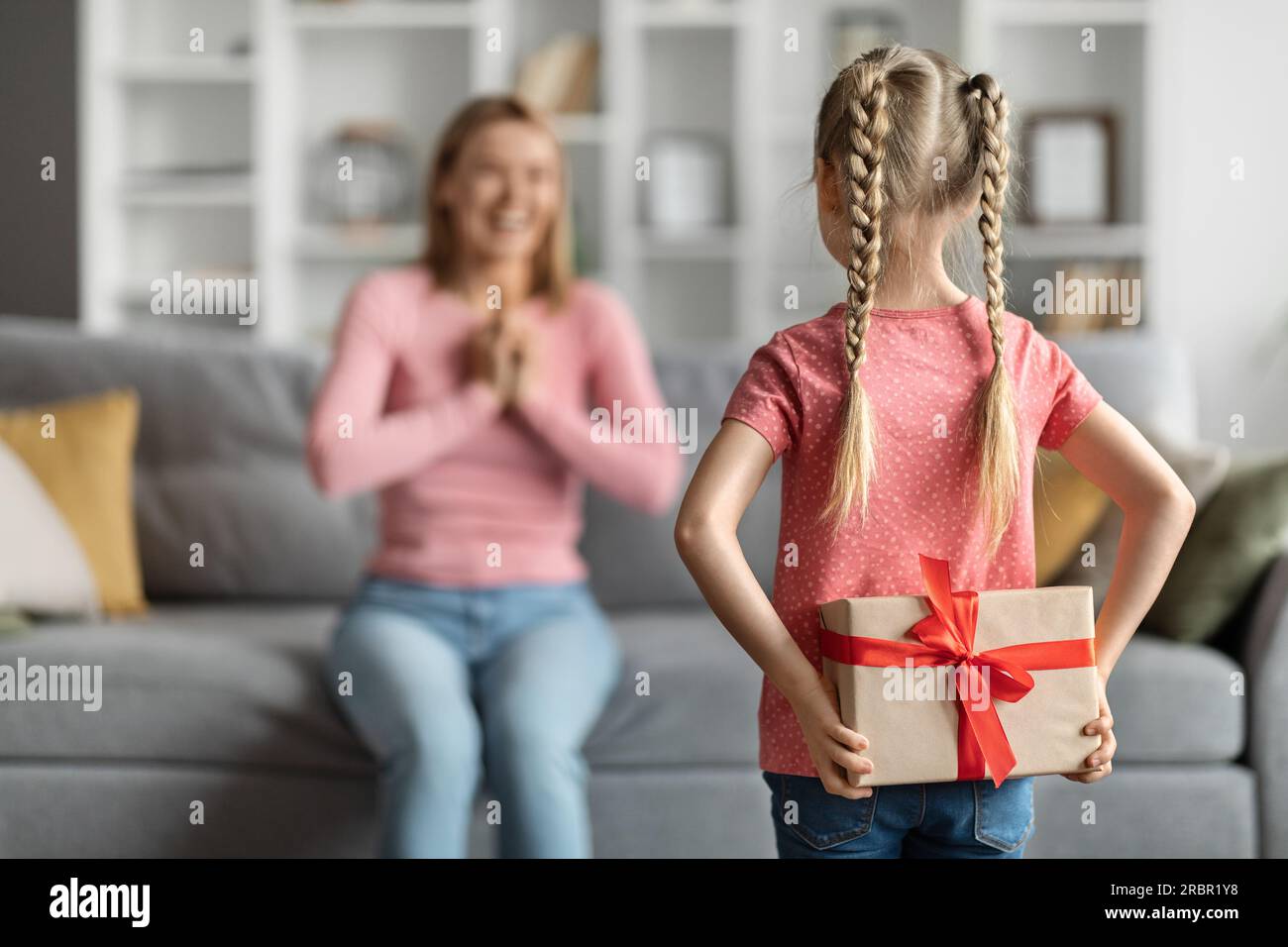 Little girl hiding gift box for mom behind back, making surprise Stock ...