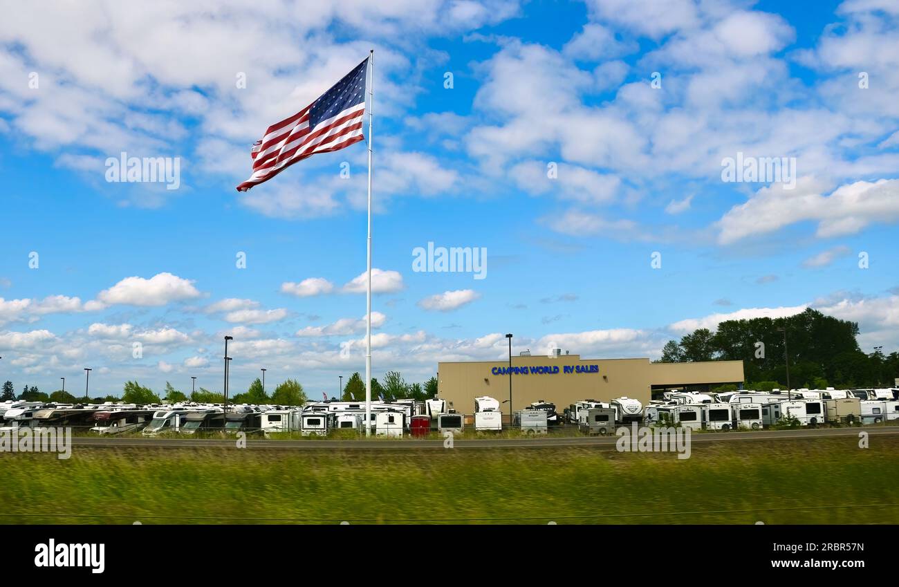 Large American flag at a Camping World RV Sales dealer with rows of ...