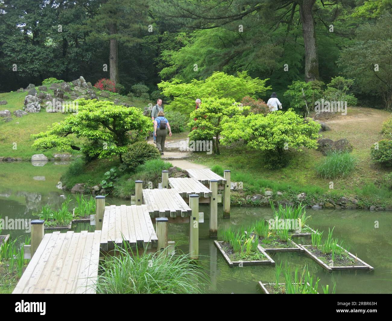 Harmony in Ritsurin Garden, Japan: a wooden bridge across the pond is ...