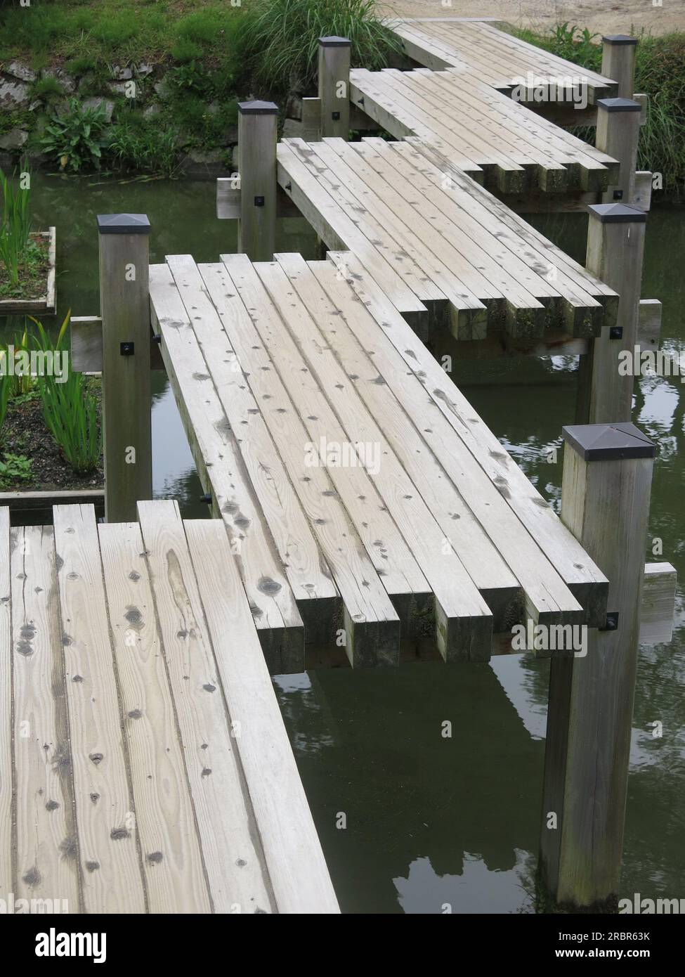 Harmony in Ritsurin Garden, Japan: a wooden bridge across the pond is ...