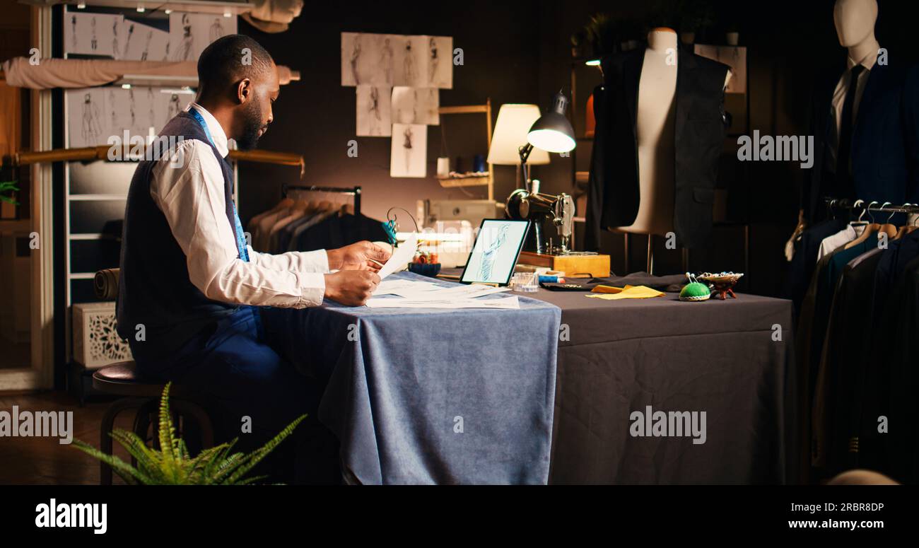 Skilled craftsman studying sketches in tailoring atelier, using ...