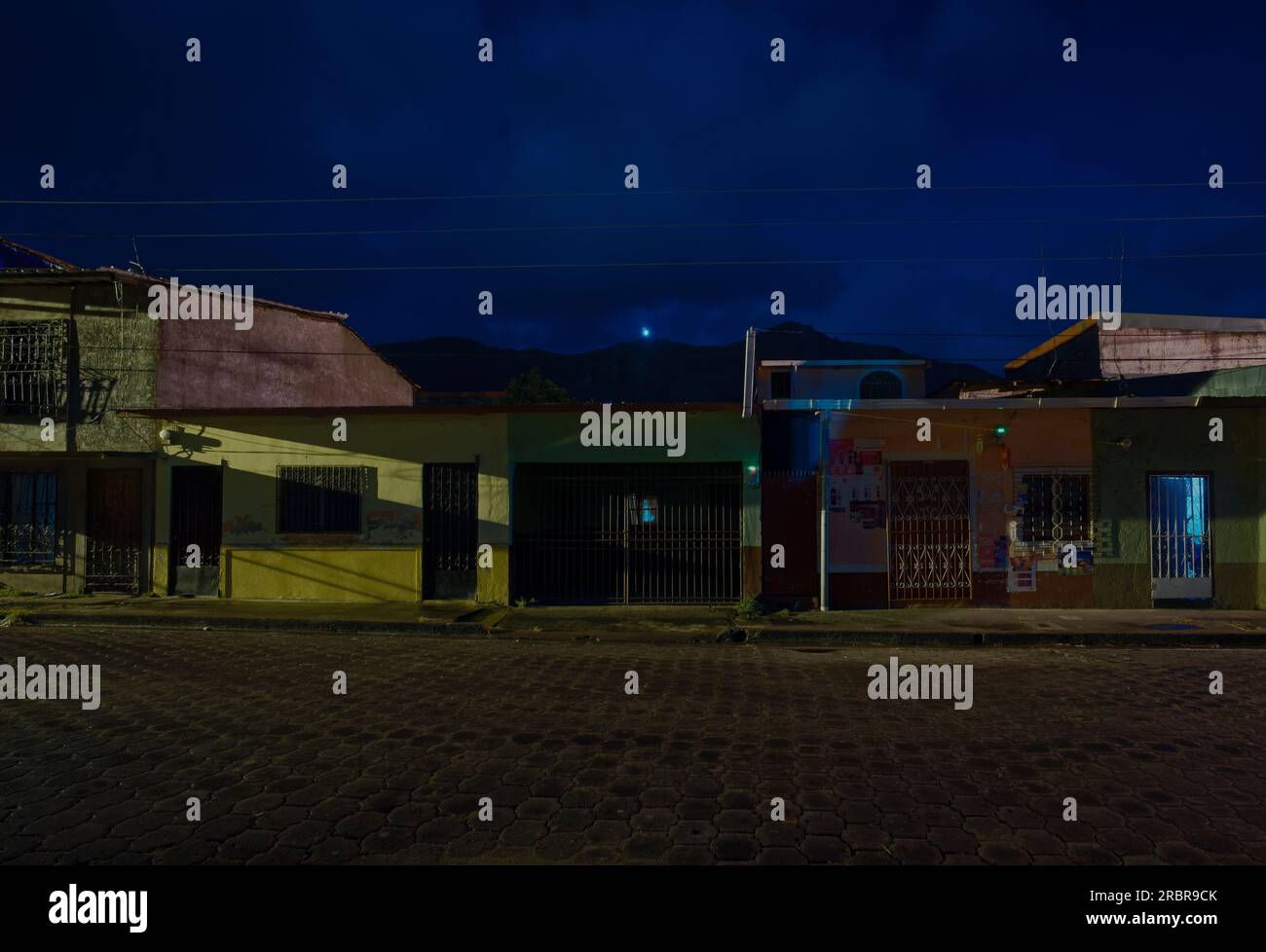 Night street lit by interior lights, some street lights and the lights ...