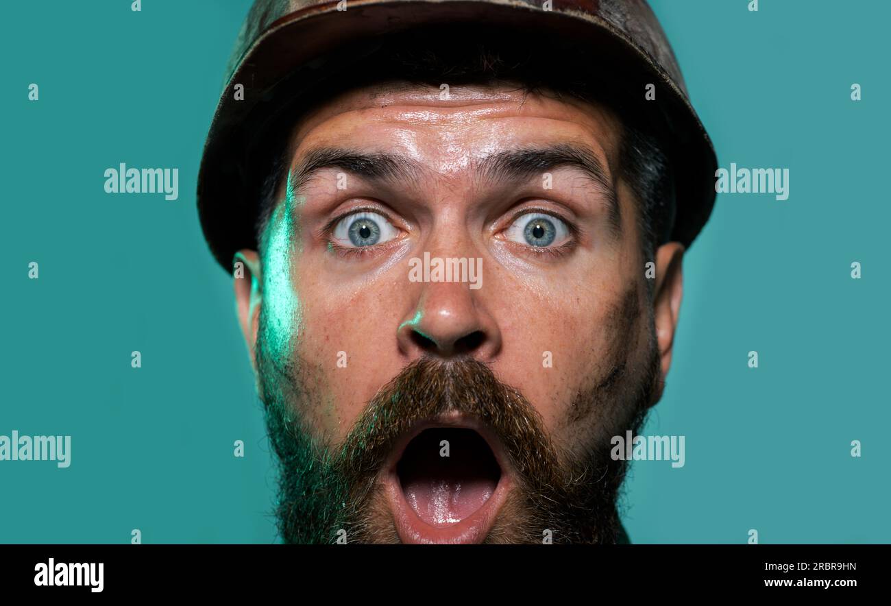 Surprised builder in protective helmet. Closeup portrait mechanical ...