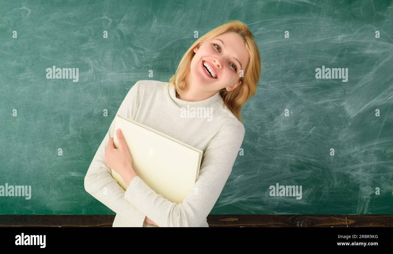 Portrait of female teacher in classroom front chalkboard. Smiling ...