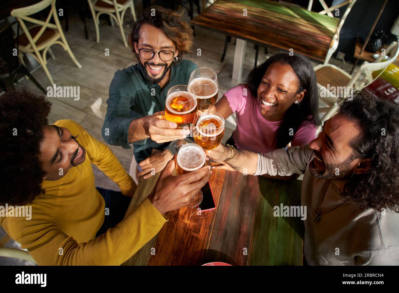 Group of multirracial young people toasting with a pint of beer and ...