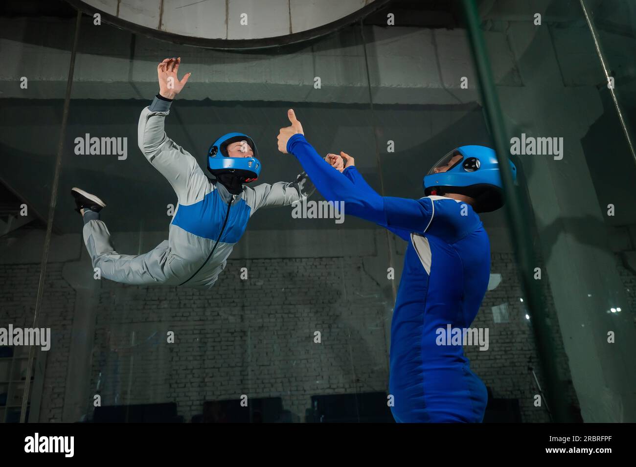 A male instructor teaches a woman how to fly in a wind tunnel. Free ...
