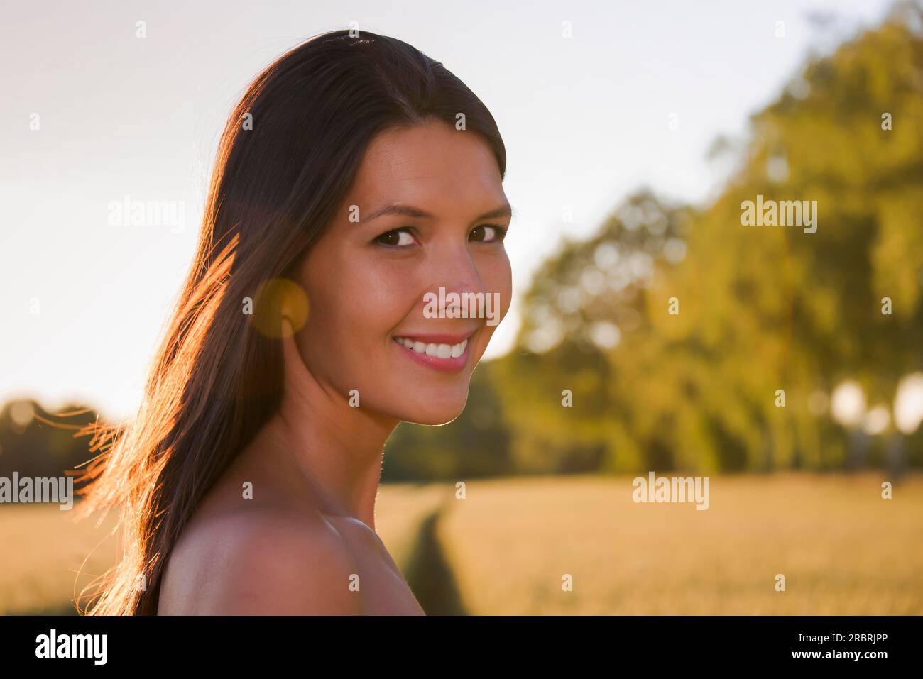 Beautiful young woman standing in wheat field, smiling Stock Photo - Alamy