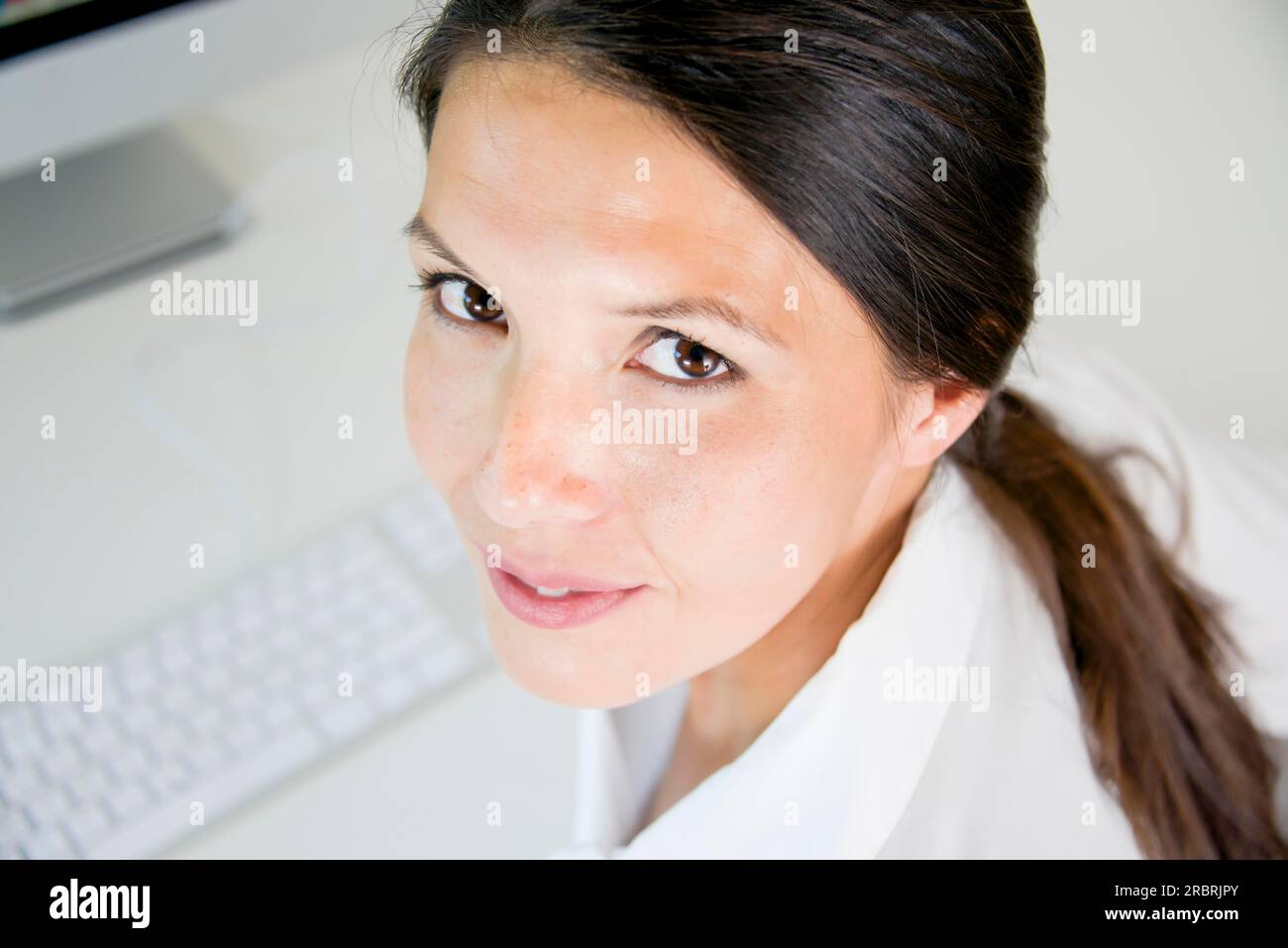 Woman sitting at working desk is smiling Stock Photo - Alamy