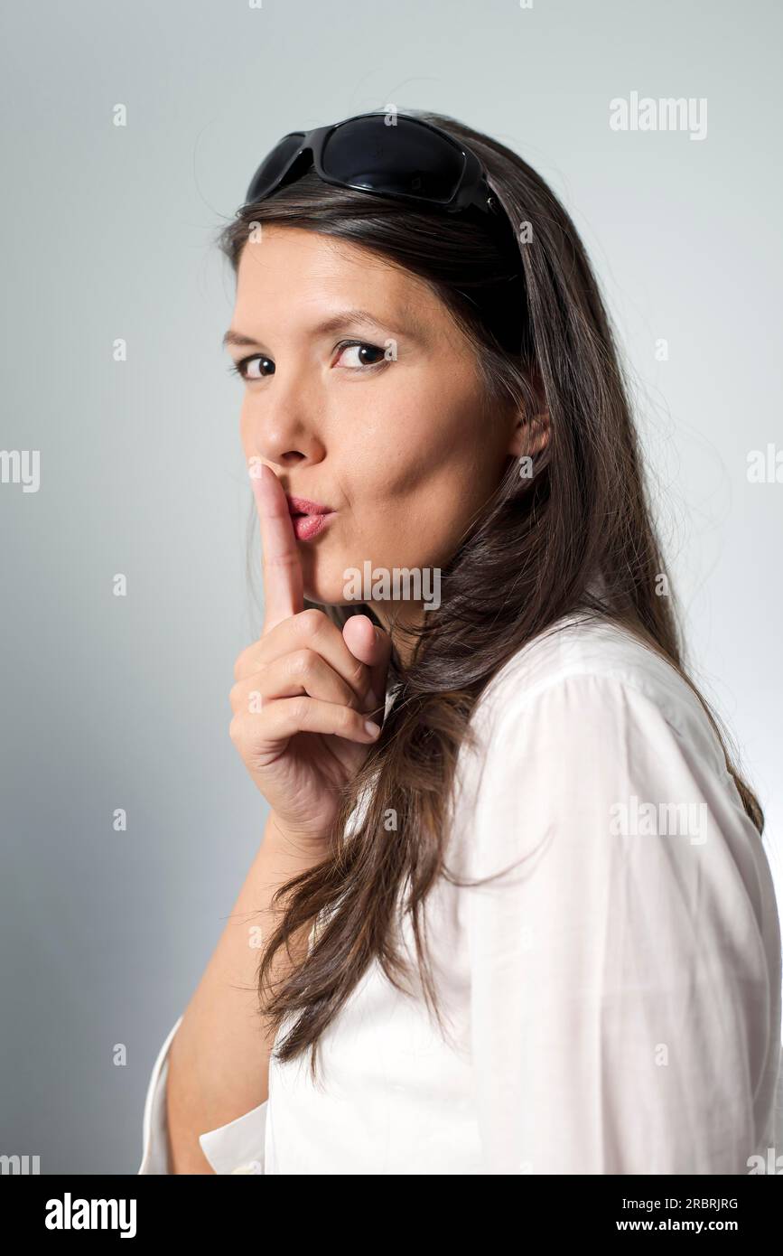 Woman putting her finger to her lips for shhh gesture Stock Photo - Alamy