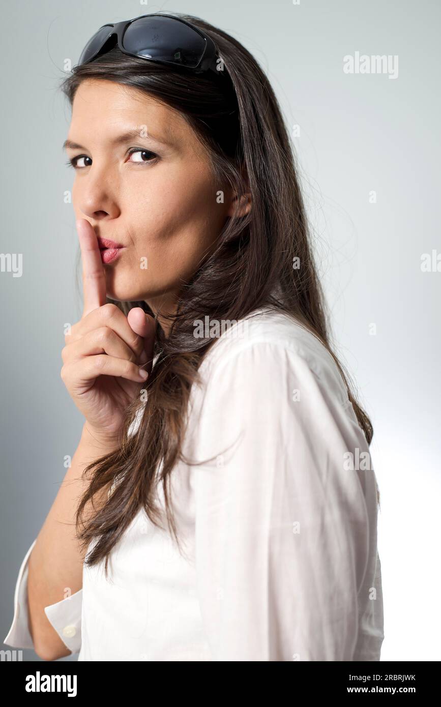 Woman putting her finger to her lips for shhh gesture Stock Photo - Alamy
