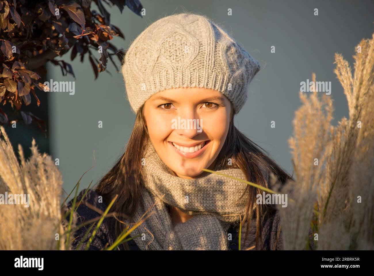 Beautiful woman wearing a warm knitted woolly cap standing smiling in a ...