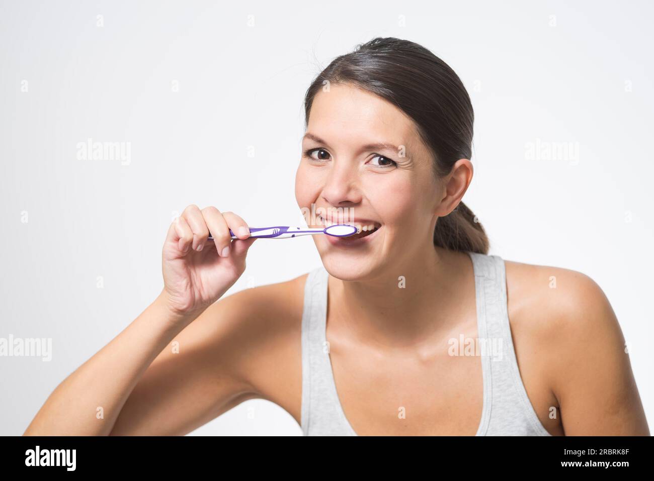 Attractive woman practising dental hygiene brushing her teeth with a ...