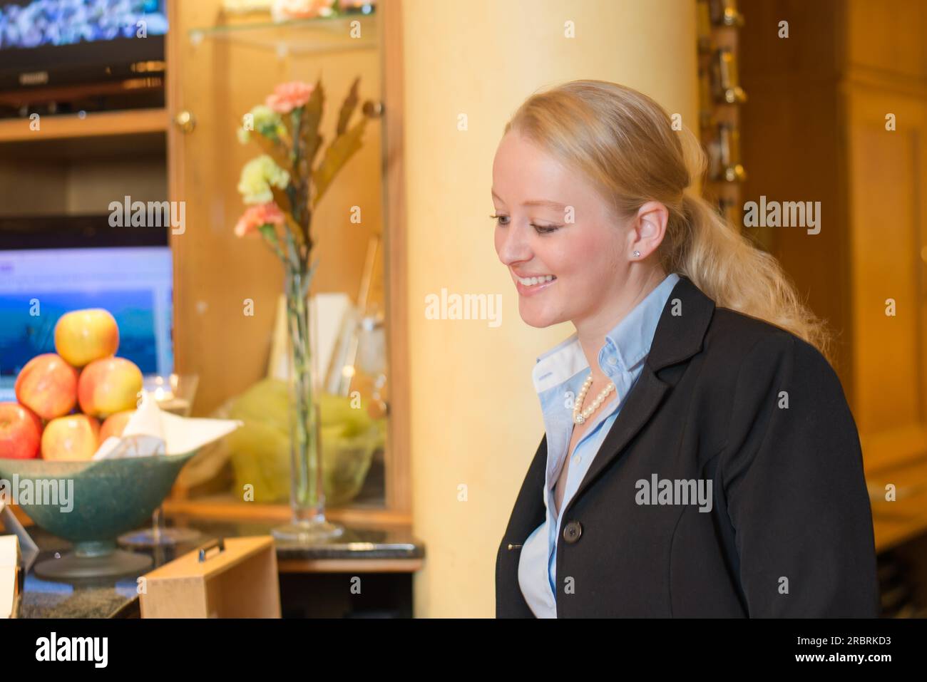 Beautiful stylish blond hotel receptionist standing behind the service ...
