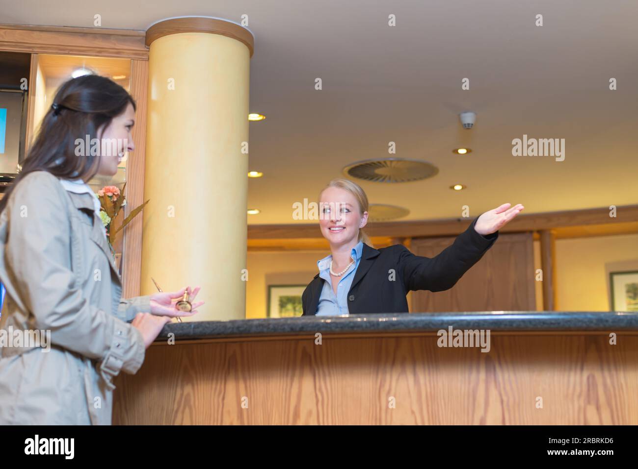 Low angle view of a beautiful friendly smiling receptionist behind the ...