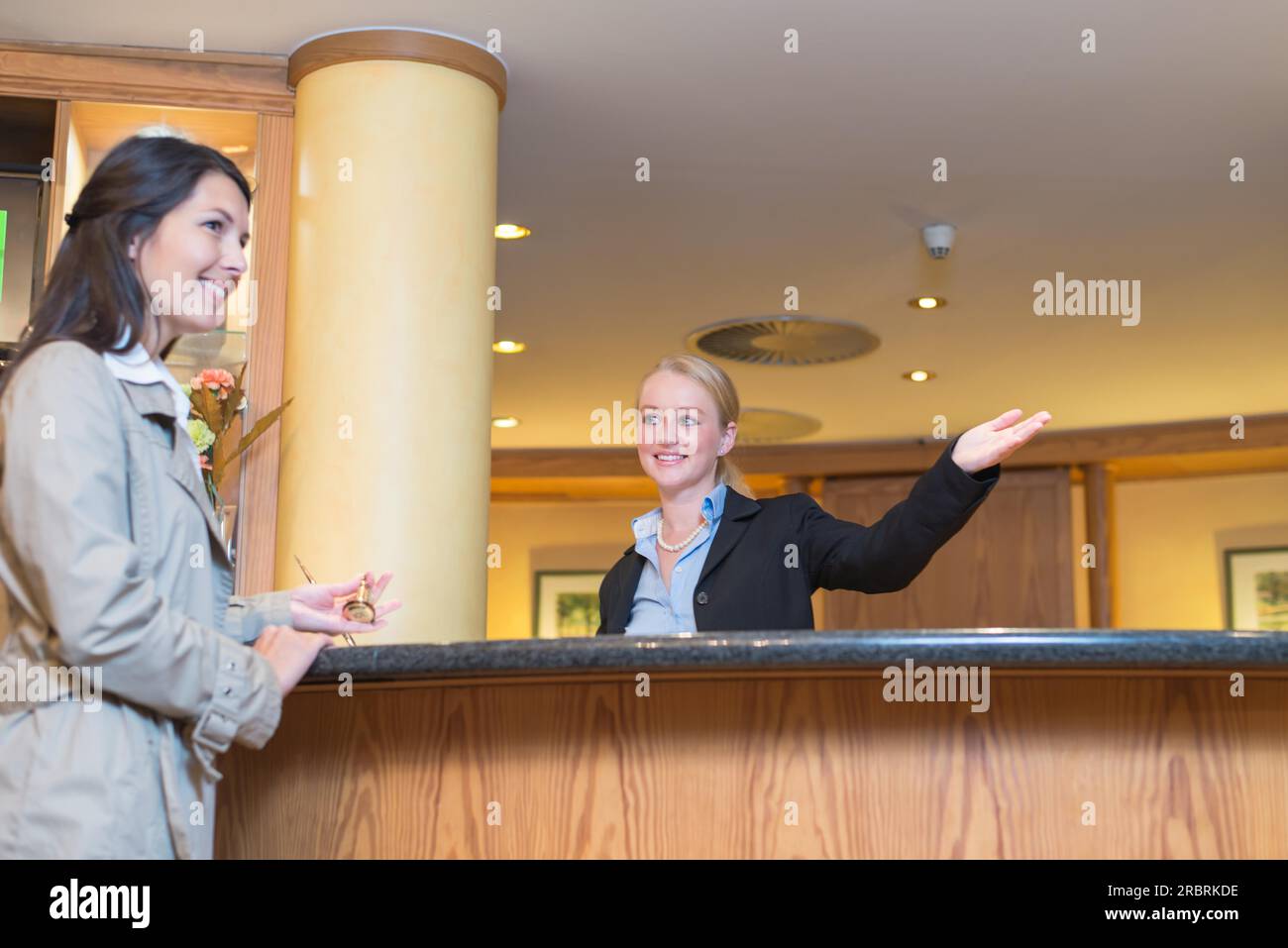 Low angle view of a beautiful friendly smiling receptionist behind the ...