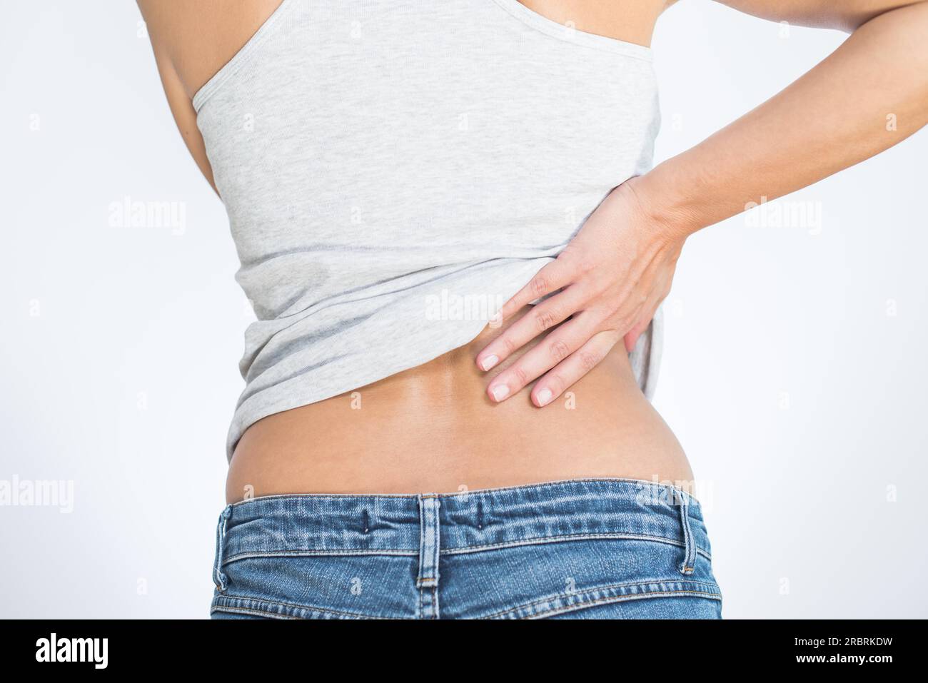 Rear view of a woman with lower back pain clutching her hands to her ...