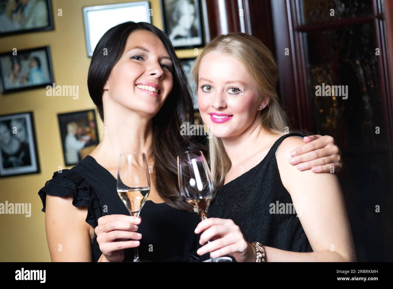 Two beautiful women in elegant black cocktail dresses celebrating with ...