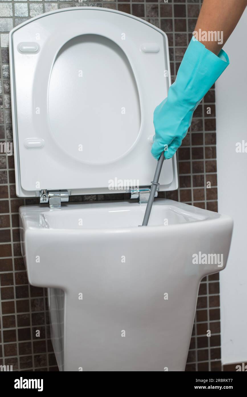 Person wearing a turquoise rubber glove cleaning under the rim of a ...