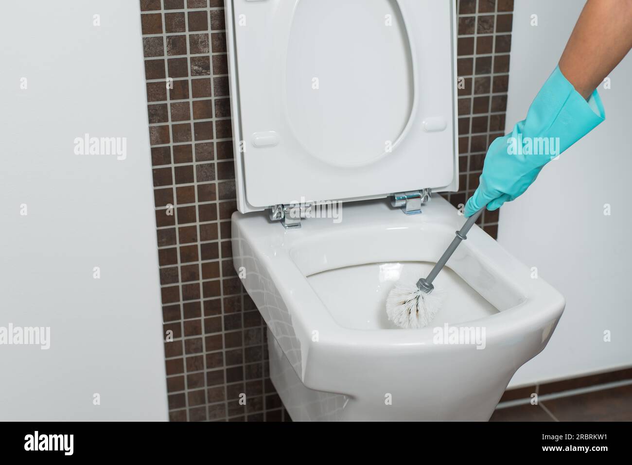 Person wearing a turquoise rubber glove cleaning under the rim of a ...