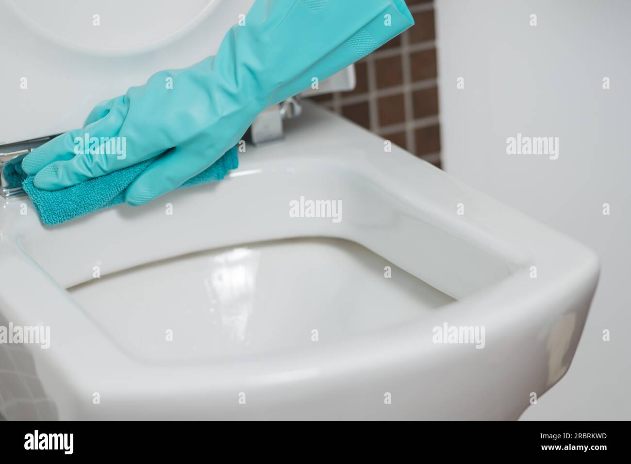 Hand of a person cleaning the toilet seat in rubber gloves with a ...