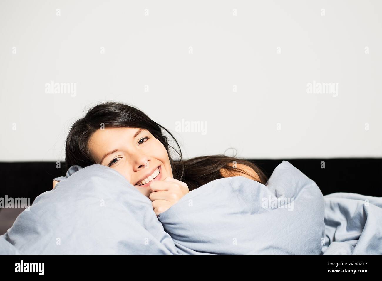 Laughing attractive young woman snuggling up in her comfortable warm ...